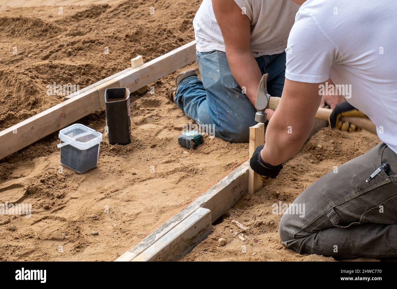 Concrete Worker using hammer to stake as they add wood framework for ...