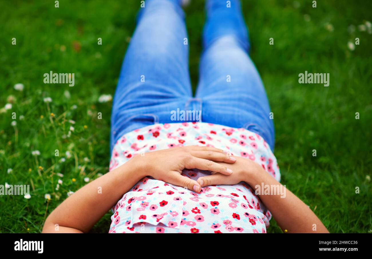Completely relaxed.... Cropped shot of a woman relaxing on a patch of ...