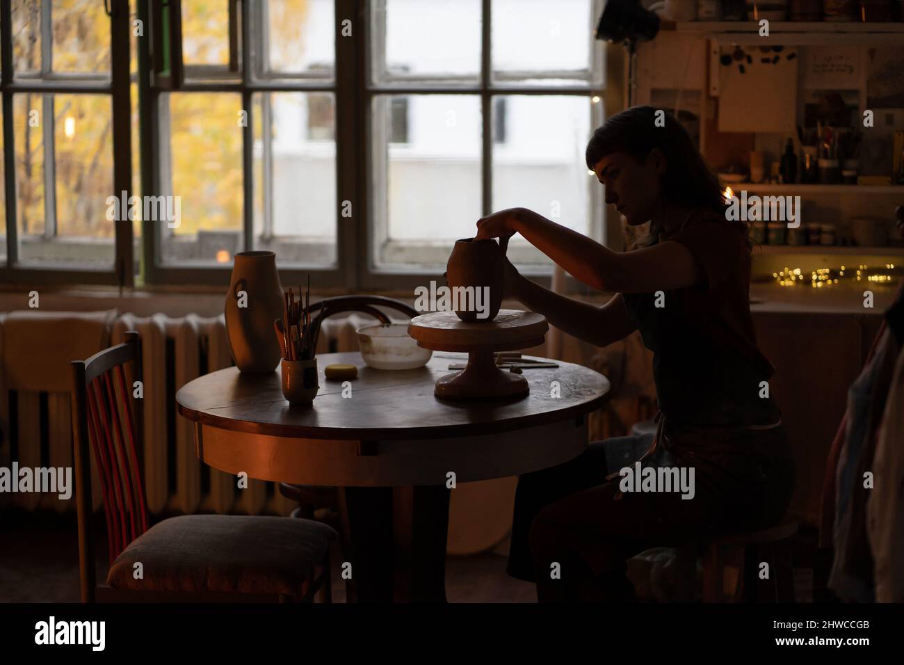 Pottery studio interior. Woman ceramics master shaping potter vase with ...