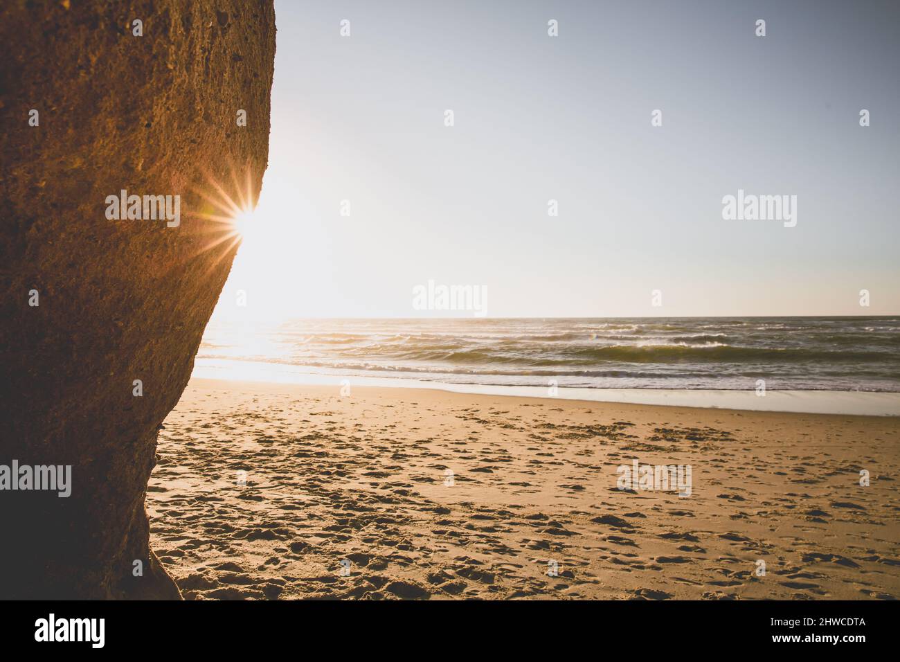 light rays of sun peeking behind the rock Stock Photo - Alamy