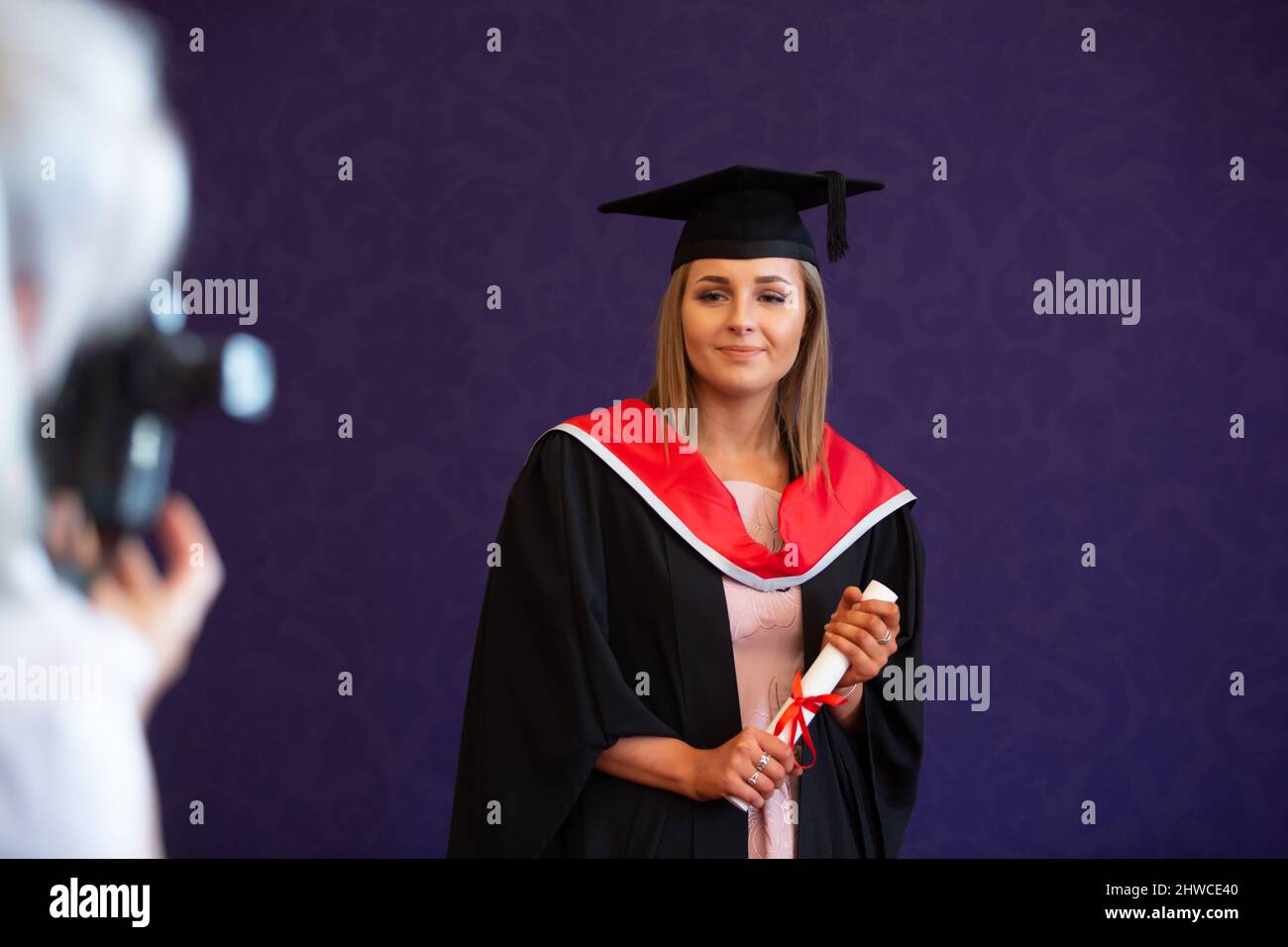 A pretty female European Graduate poses for the official photographer ...