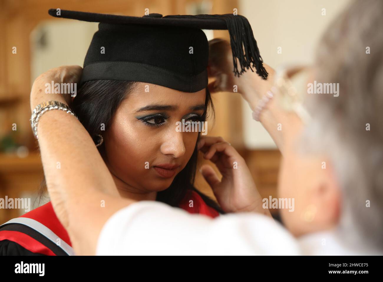 A pretty Asian female Graduate getting her mortarboard fitted at their ...