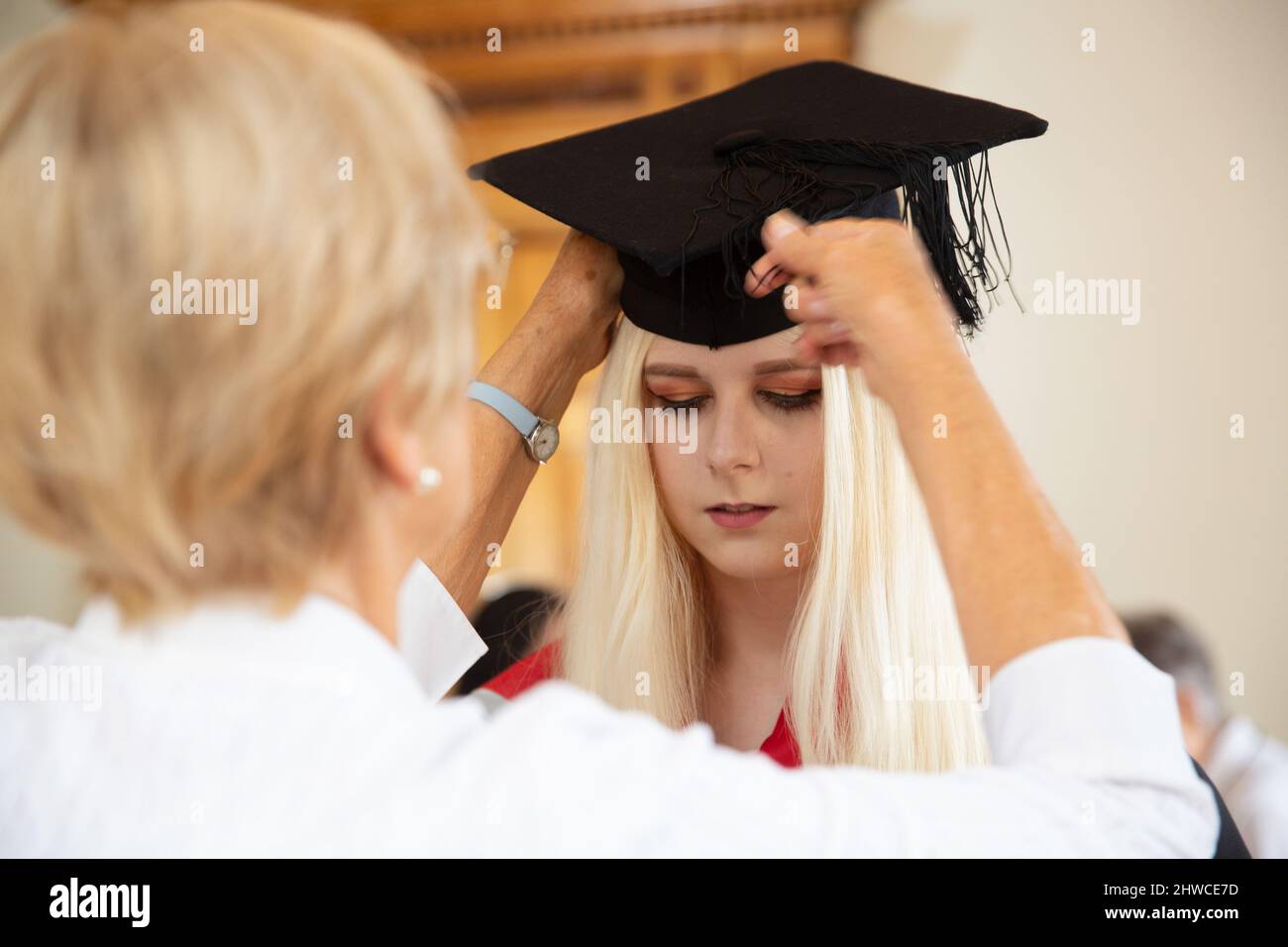 A European female Graduate getting her mortarboard fitted at her ...