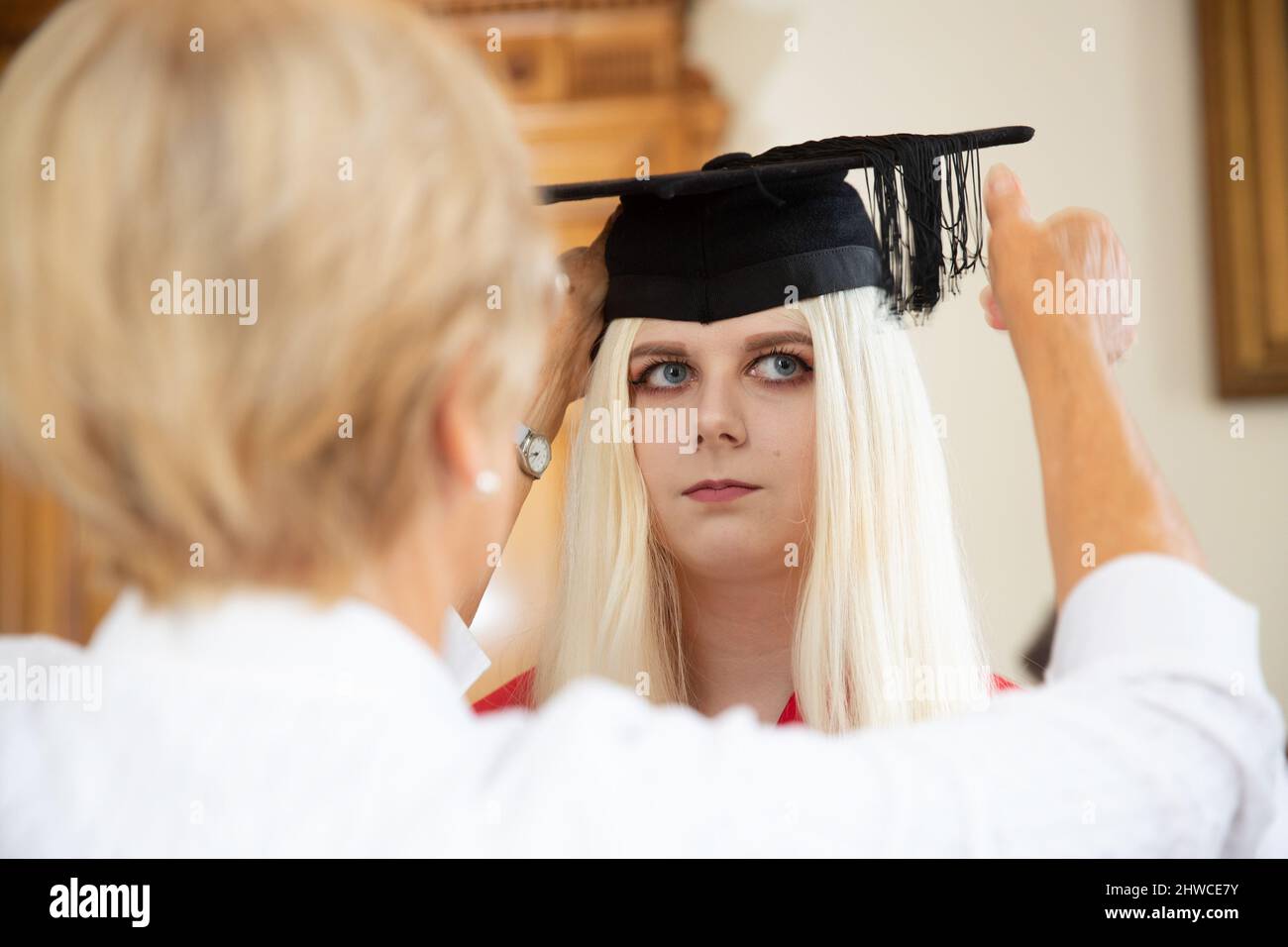 A European female Graduate getting her mortarboard fitted at her ...