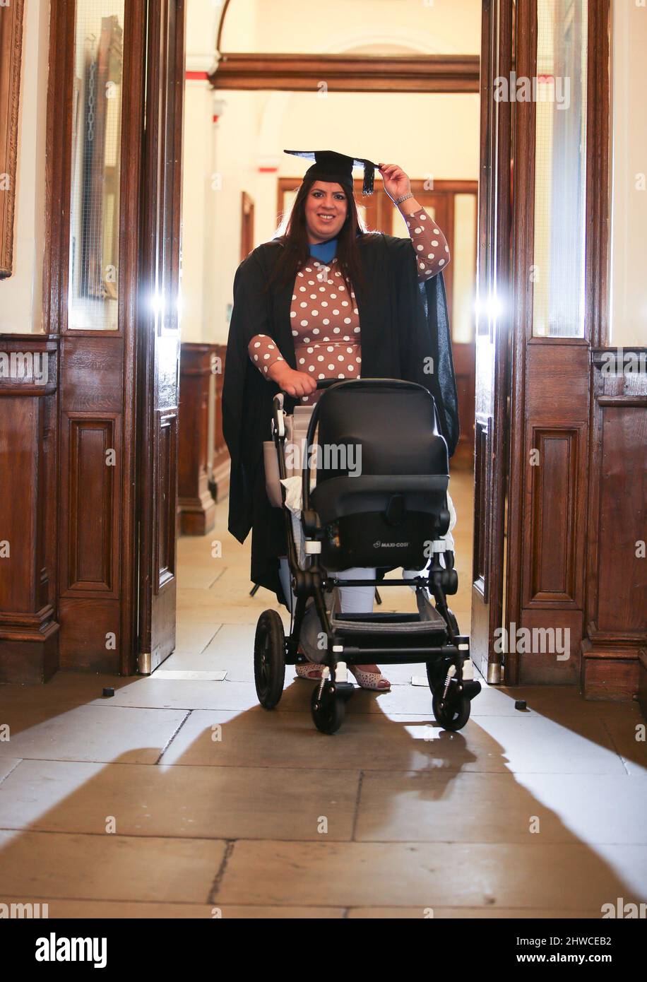A european female graduate arriving with pushchair at their graduation ...