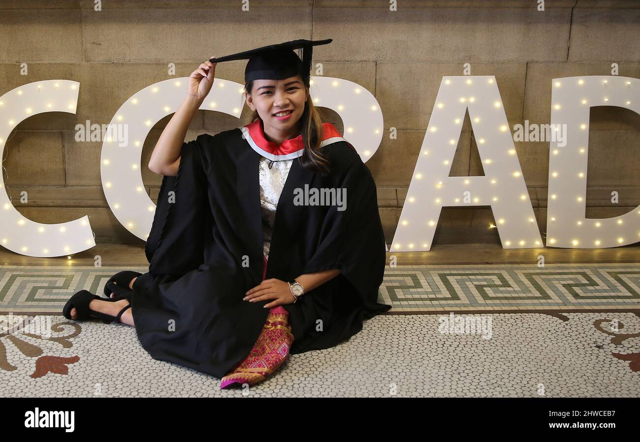 A pretty Asian female graduate poses for photographs at her graduation ...