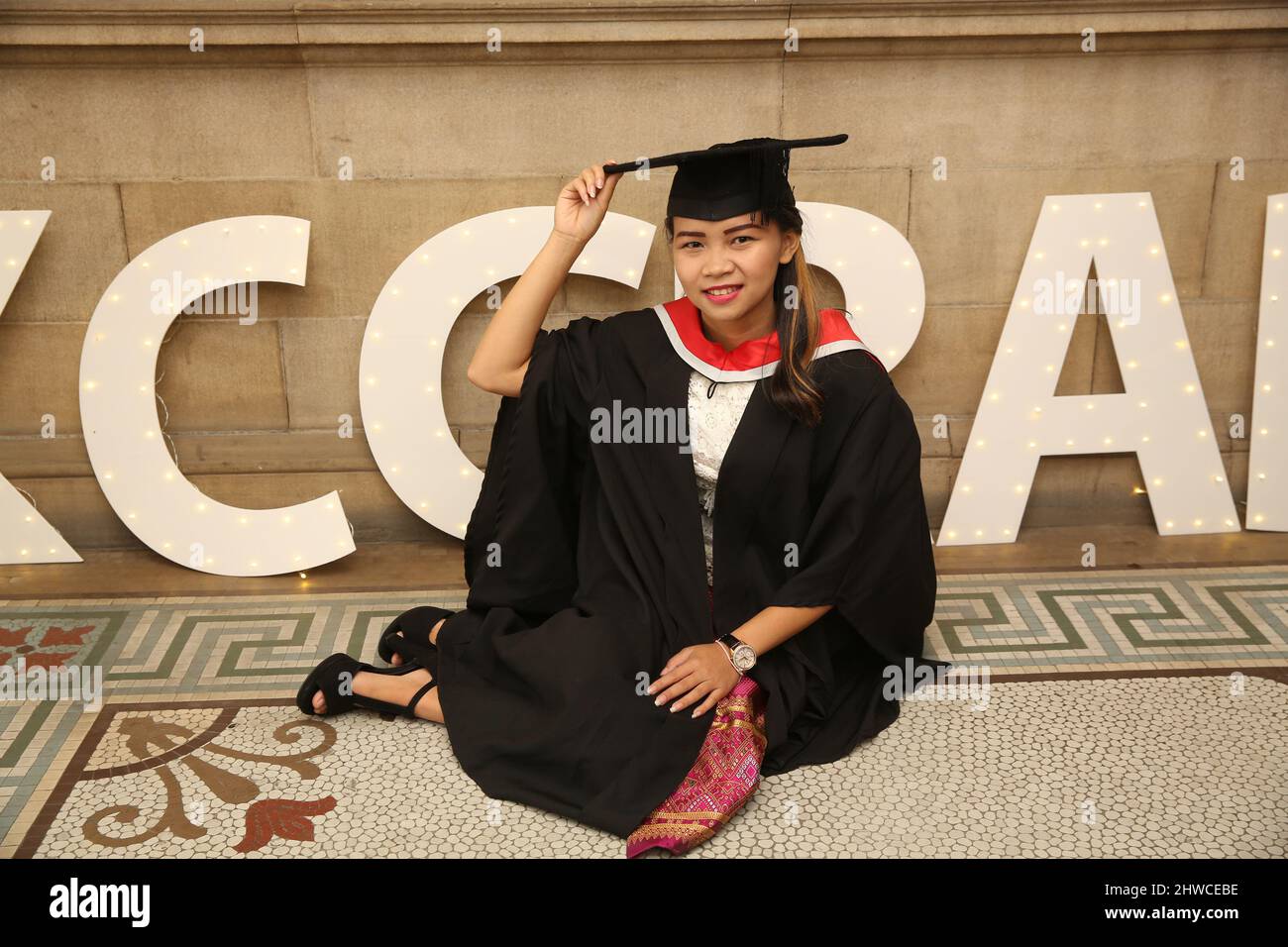 A pretty Asian female graduate poses for photographs at her graduation ...