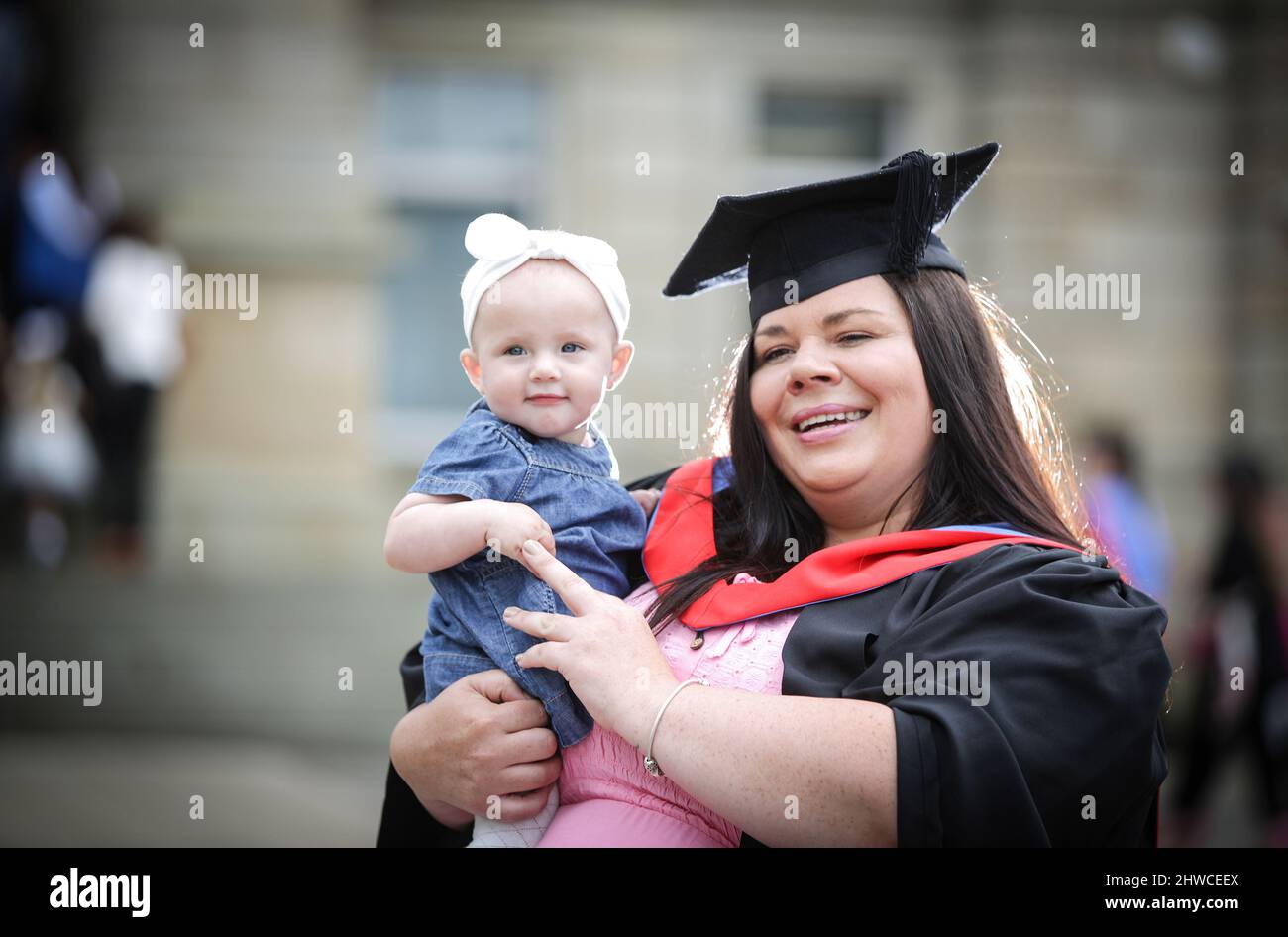 Mum holds her baby daughter on her Graduation day, Graduates gather to ...