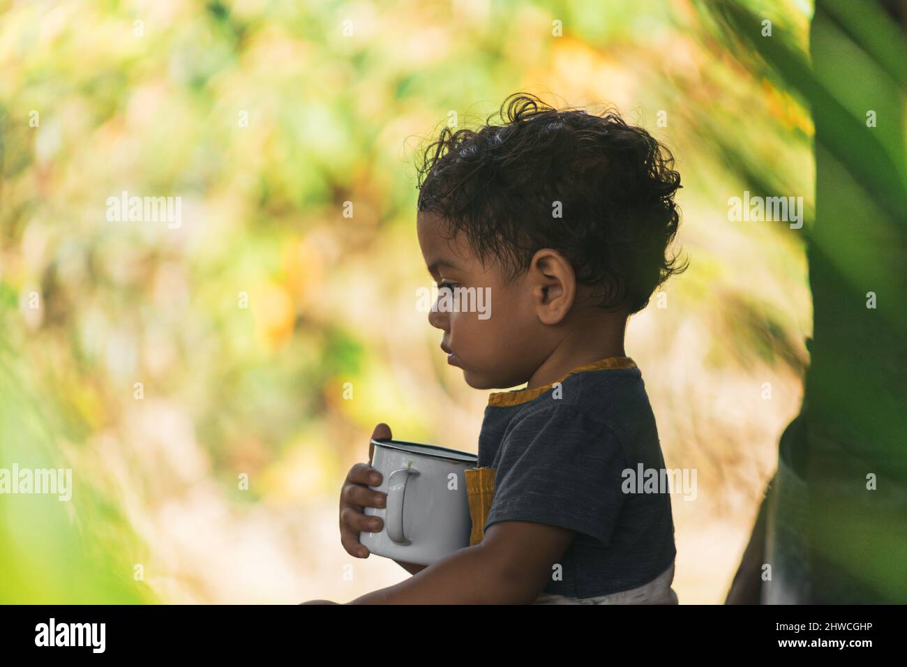 latin boy drinking coffee in a white cup, in a natural environment ...