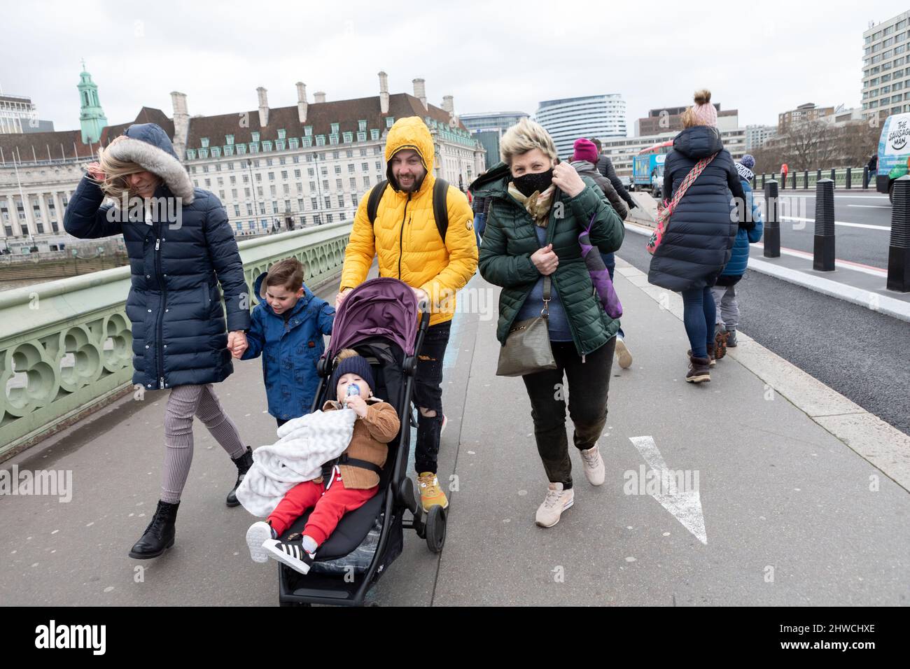 A family navigates its way agains the strong winds across Westminster ...
