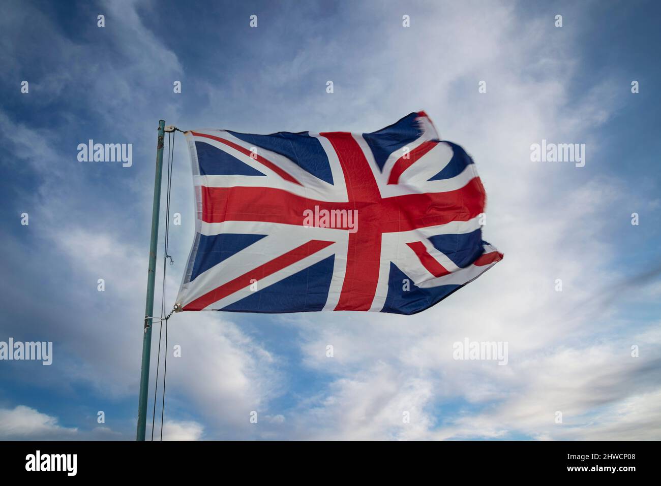 Union Jack Flag blowing in the wind against a blue sky Stock Photo - Alamy