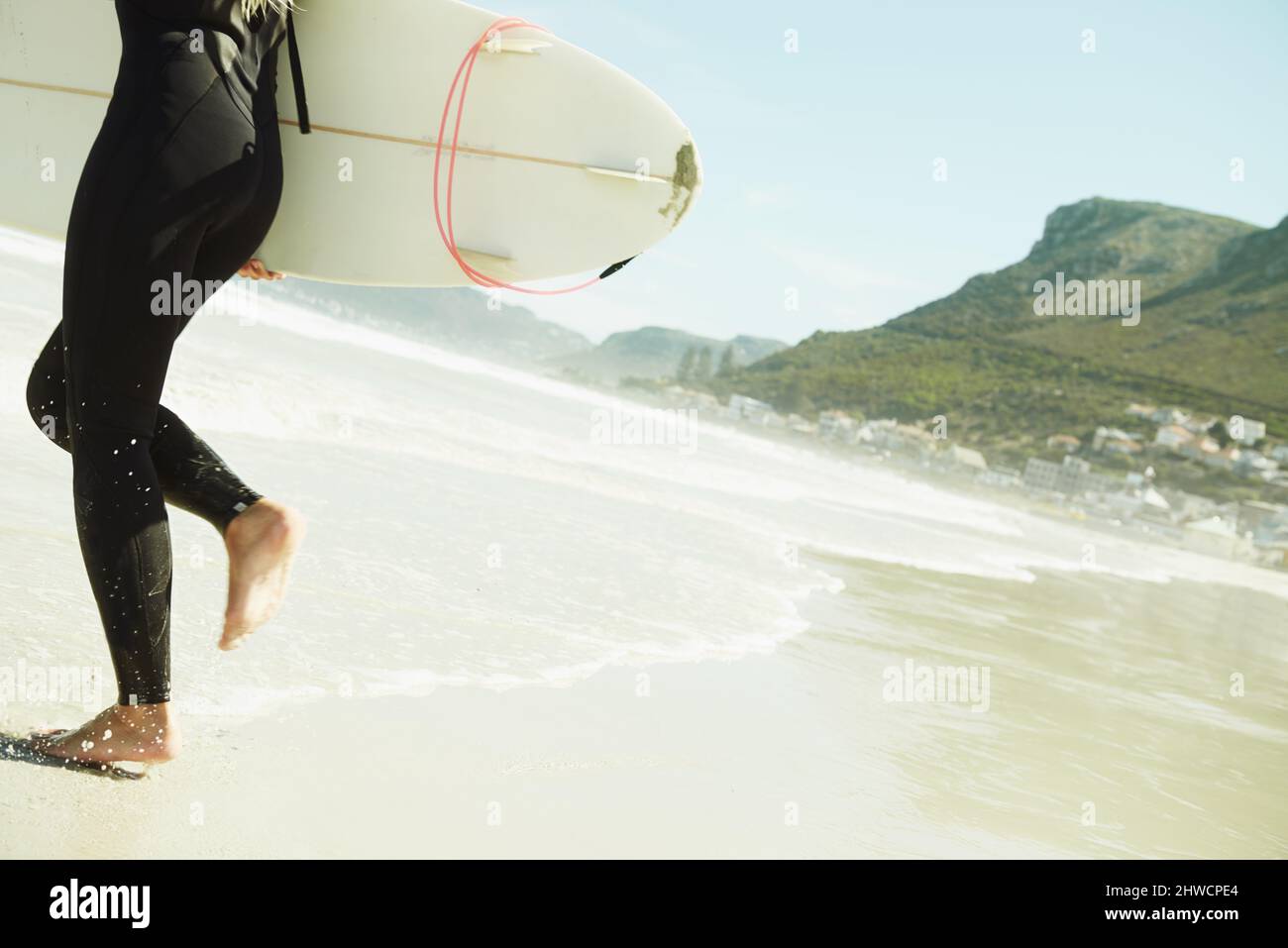 Going for it. A female surfer running into the ocean with her surfboard ...