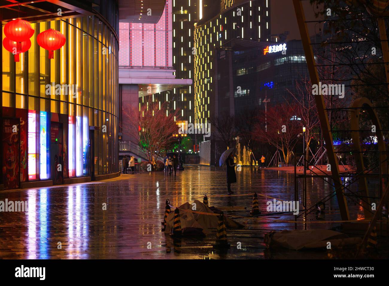 A man holding an umbrella seen at the entrance of a shopping mall in ...