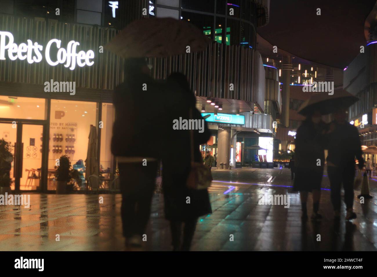 Pedestrians with umbrellas walk along an alley in Time Square district ...