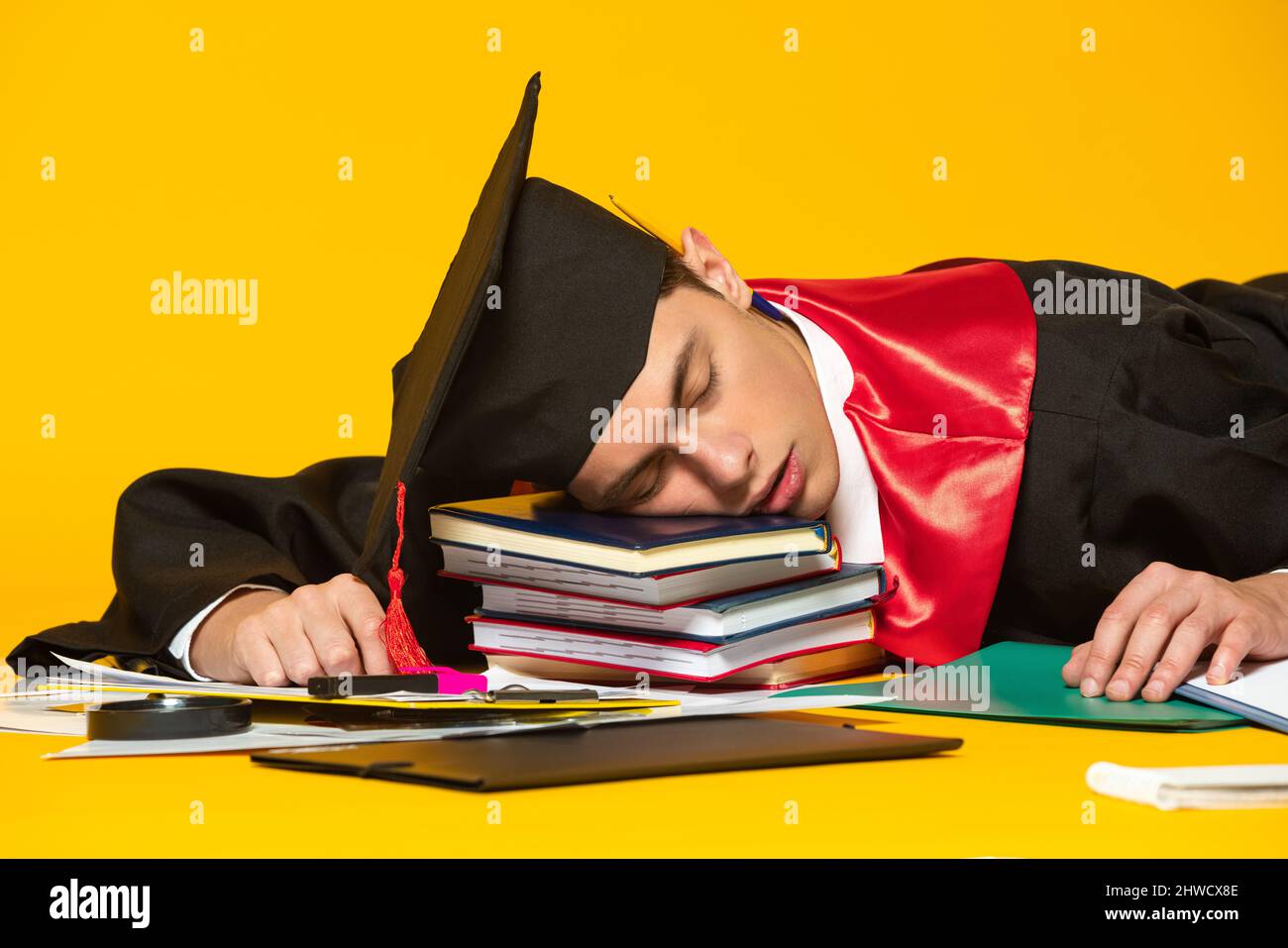 Portrait of young man, student in graduation cap and gown sleeping on ...