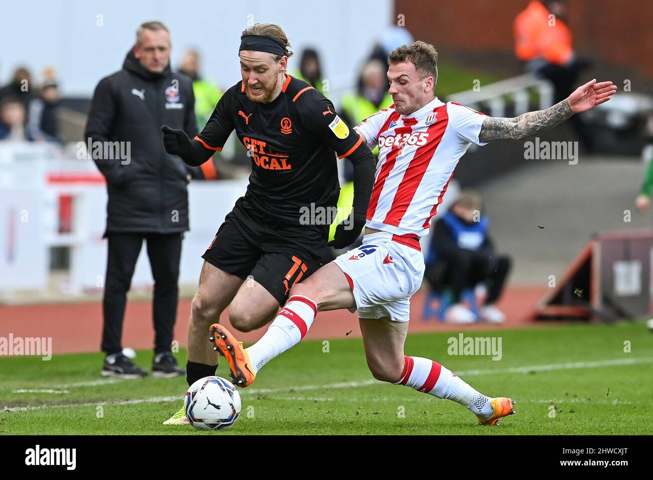 Josh Bowler #11 of Blackpool hurdles the challenge from Josh Tymon #14 ...