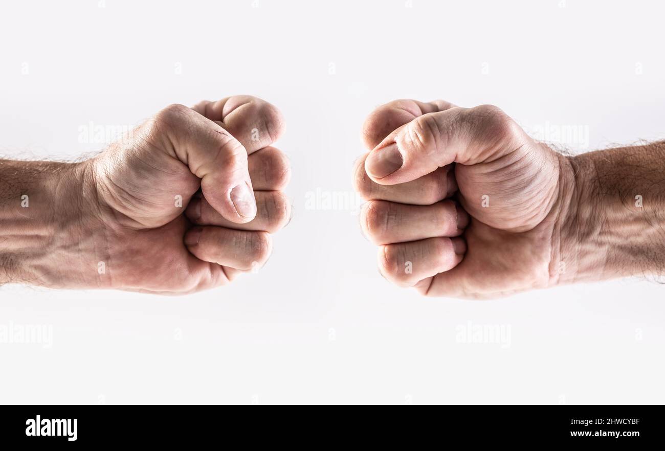 Two fists opposite one another are about to touch on an isolated white ...