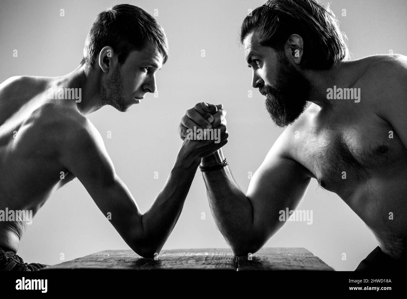 Heavily muscled bearded man arm wrestling a puny weak man. Arms ...