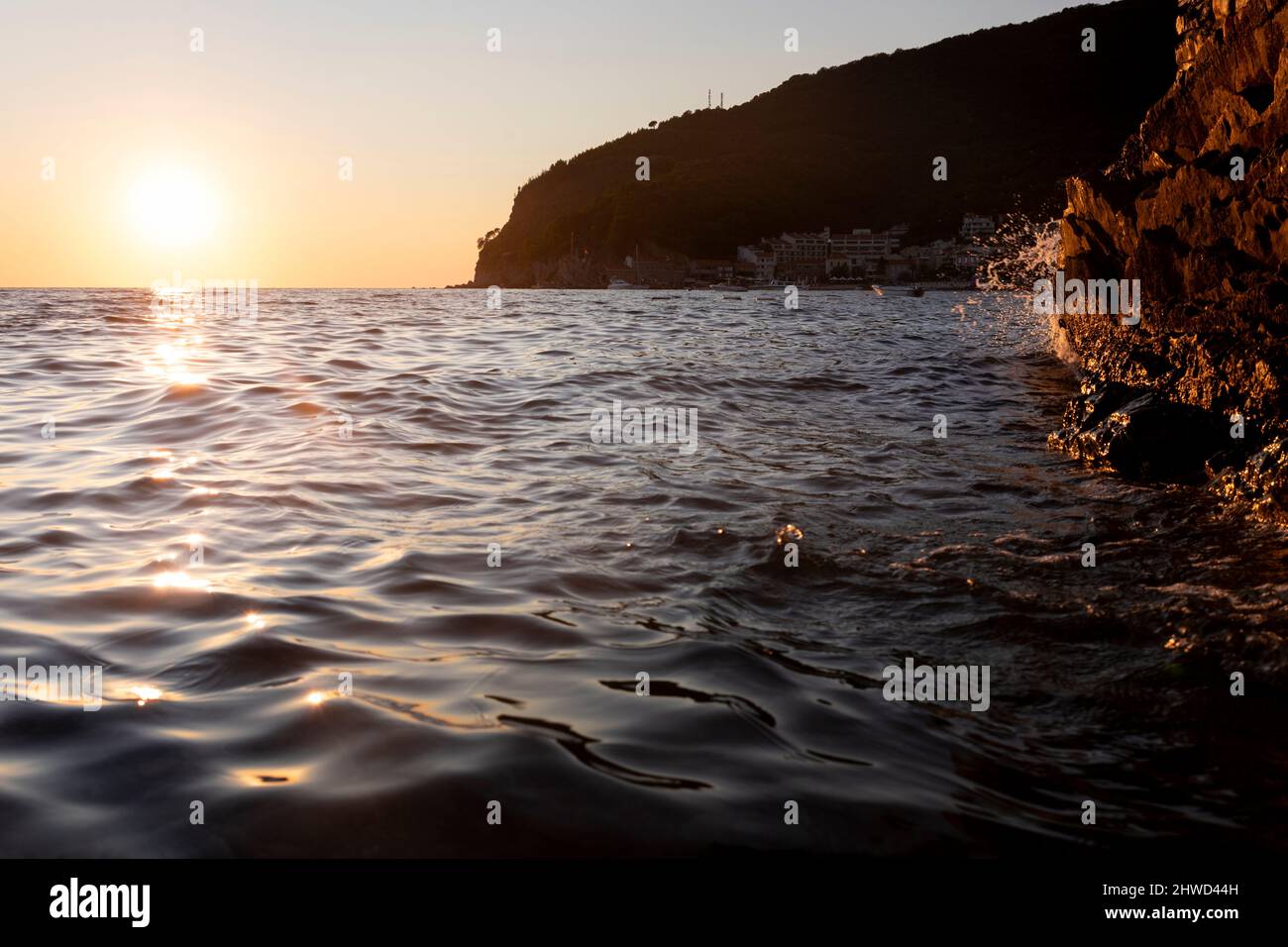 Sea water splashing at rocks at sunset Stock Photo - Alamy