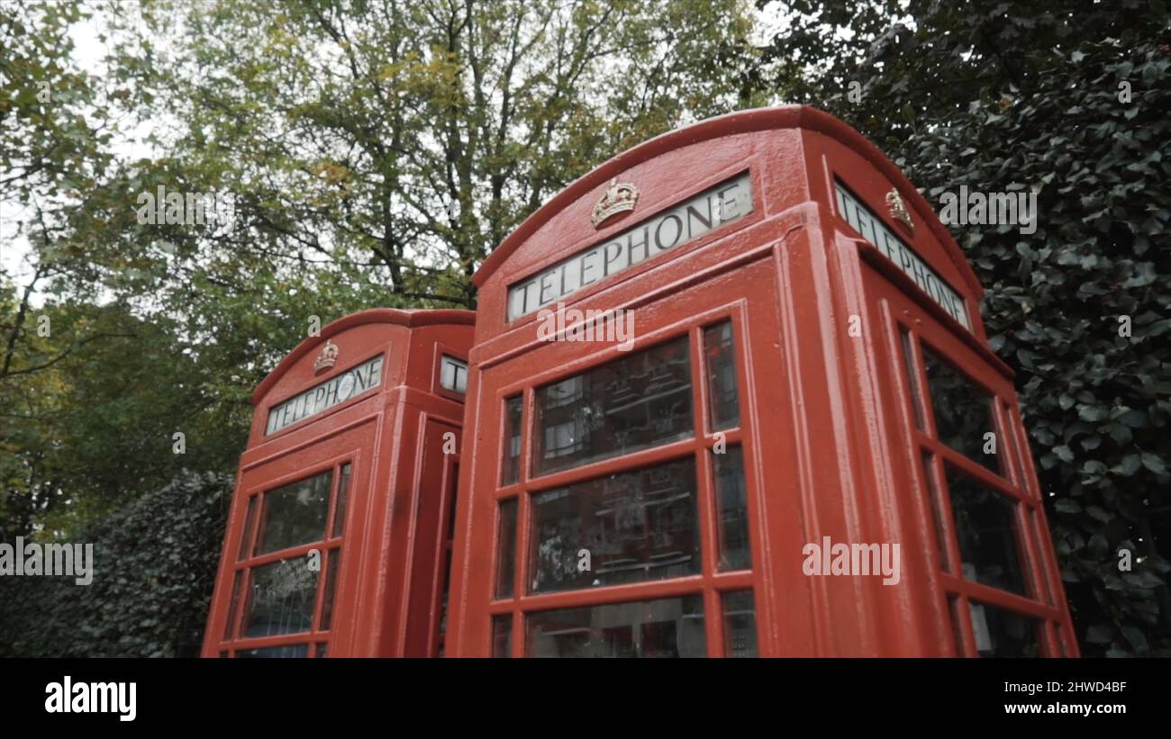 Close-up of the traditional red telephone boxes in London against green ...
