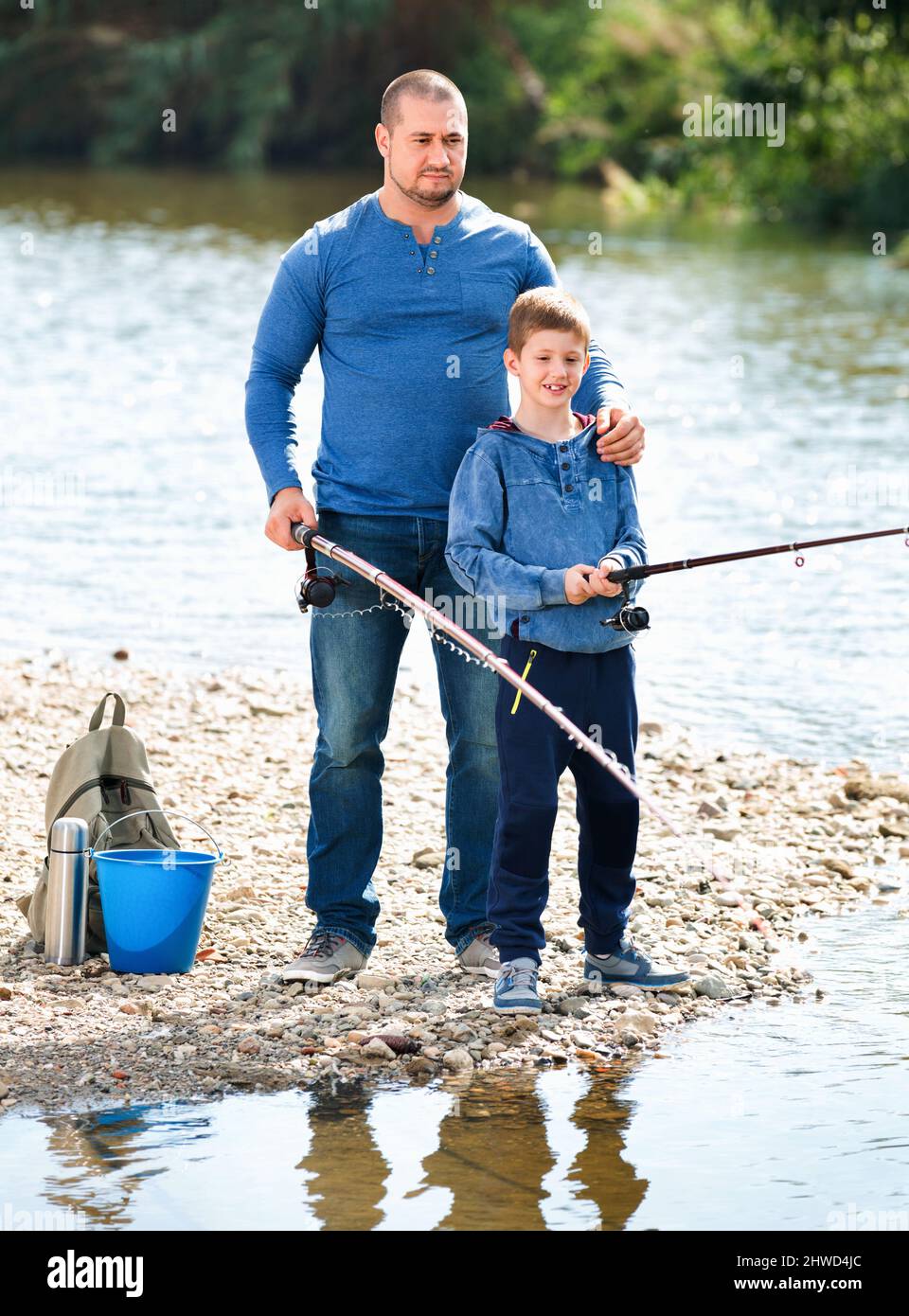 Portrait of positive cheerful father and son fishing with rods in ...