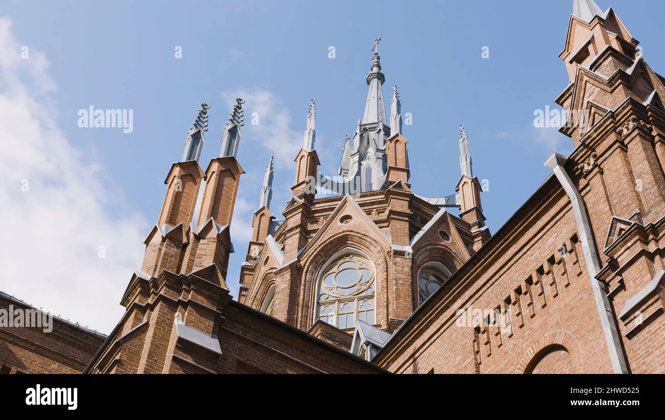 Red brick Gothic Church on background blue sky. Action. Bottom view of ...