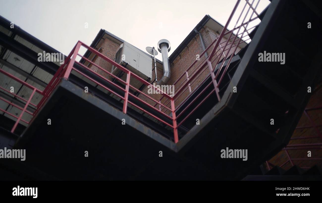 Bottom view of fire escape at brick building. Action. Emergency exit is ...