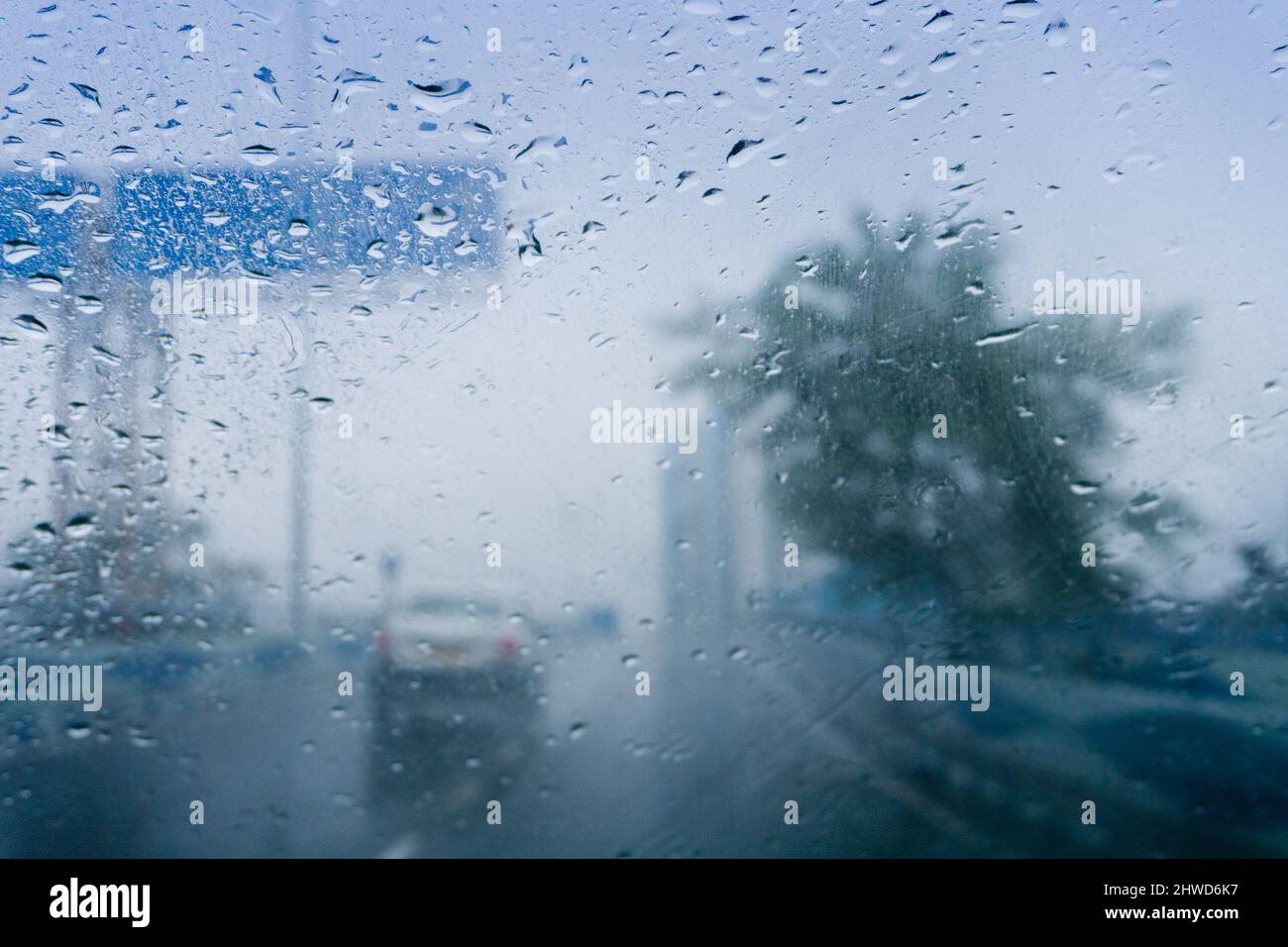 Raindrops falling on car's windshield glass, abstract blurs of road ...