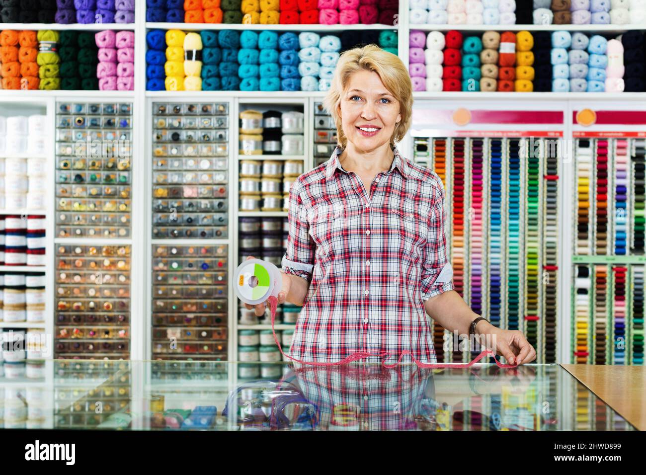 Mature glad friendly woman customer picking various ribbon in sewing department Stock Photo - Alamy