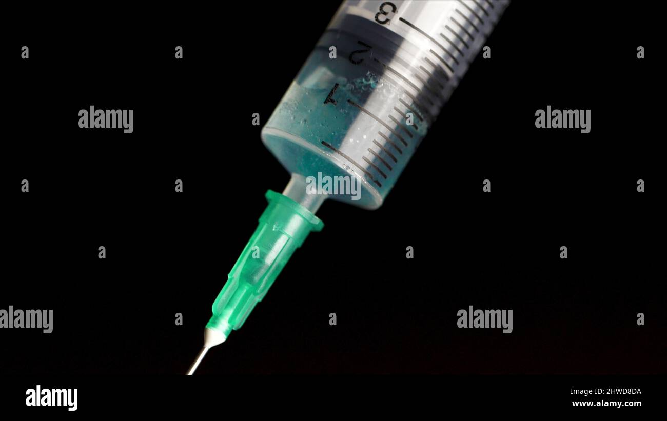 Taking vaccine into a glass syringe from a ampule on a black background ...