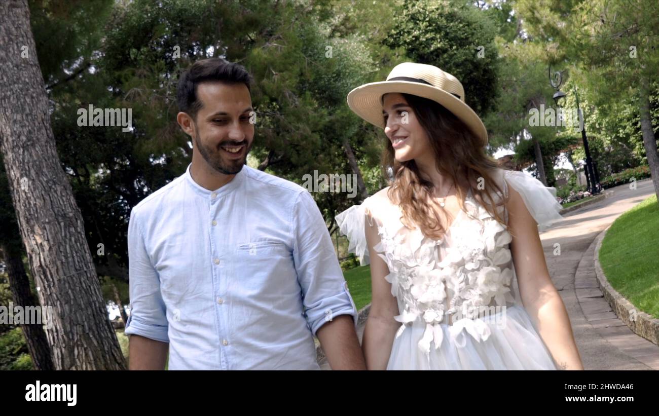 Newlyweds are smiling and holding hands in park. Action. Beautiful ...