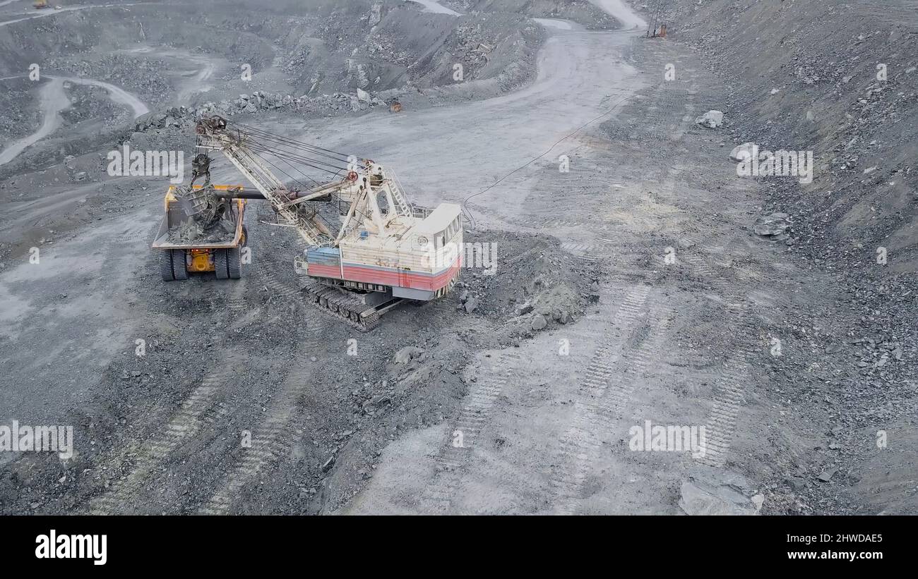 Top view of excavator in open pit. Excavator falls asleep rubble in ...