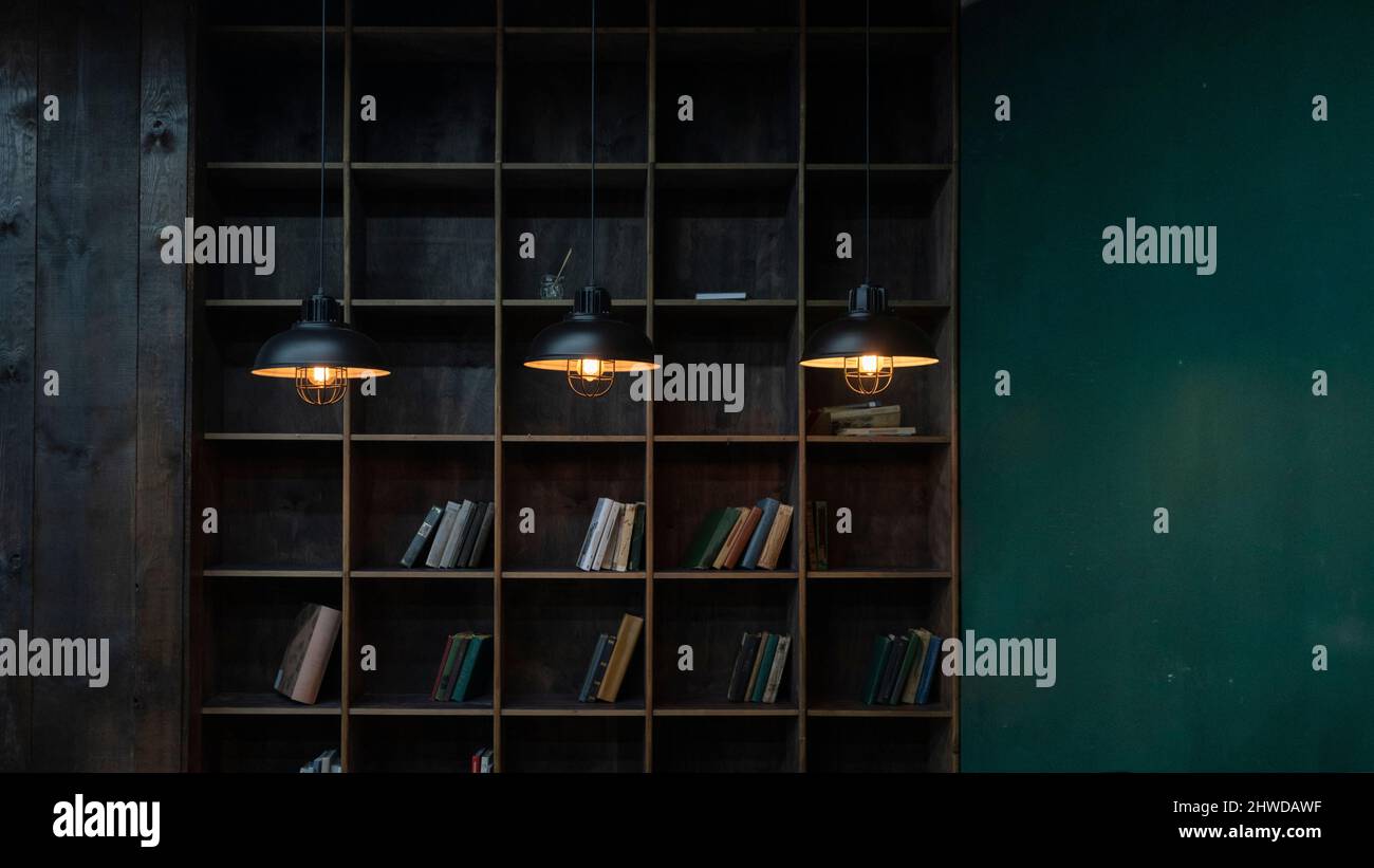 Bookshelf with books in the library illuminated by lamps Stock Photo ...