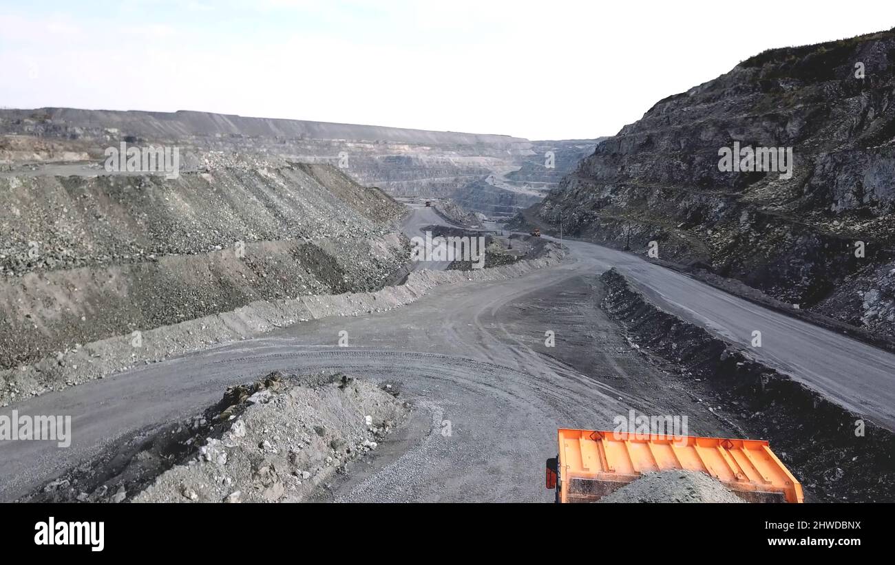 Dump truck is at quarry. Top view of driving orange dump truck with ...