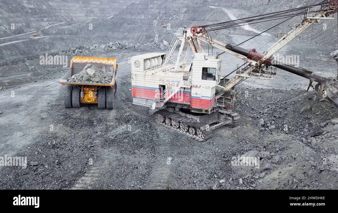 Top view of excavator in open pit. Excavator falls asleep rubble in ...