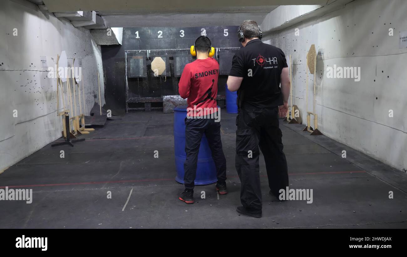 Man shoots at the shooting range with the instructor. Man trains ...