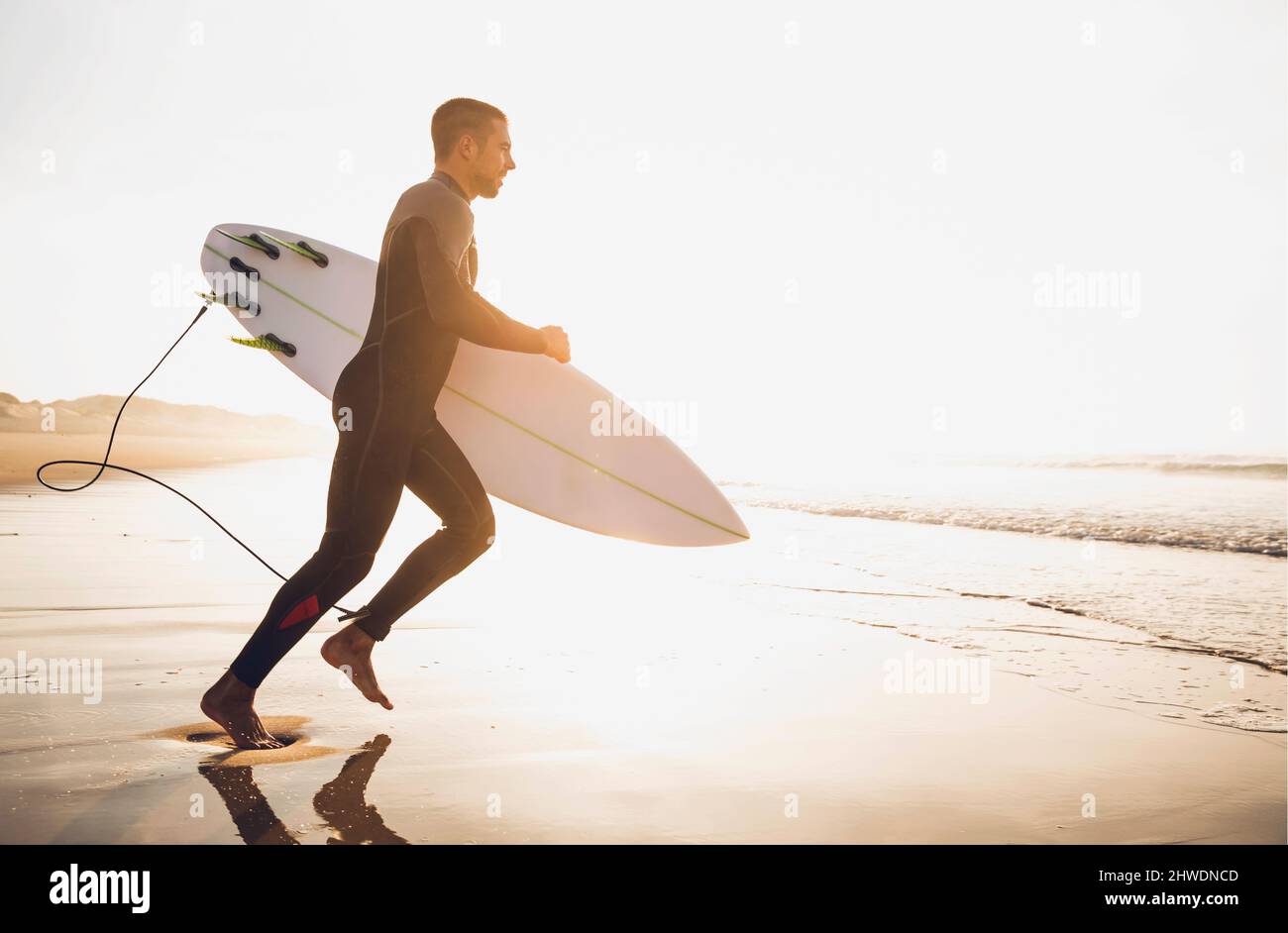A surfer with his surfboard running to the waves Stock Photo - Alamy