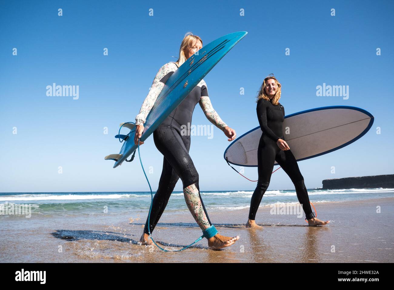 2 Caucasian surfer women getting out of the water with their surfboards ...
