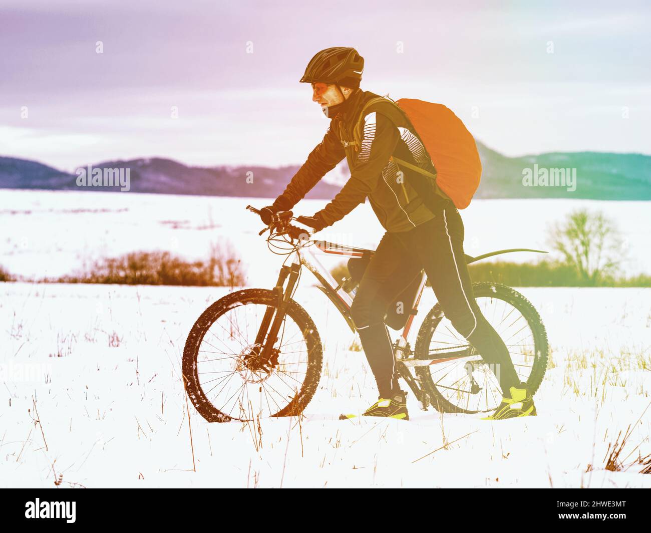 Sport cyclist pushing bike in the hardest and snowy landscape during ...