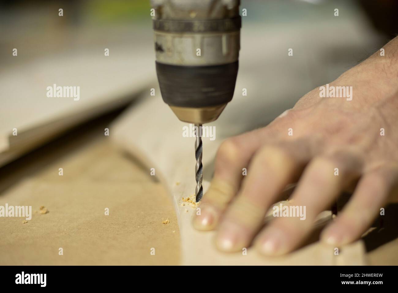 Drill bit in wood. Drilling hole in board. Guy works with tool ...