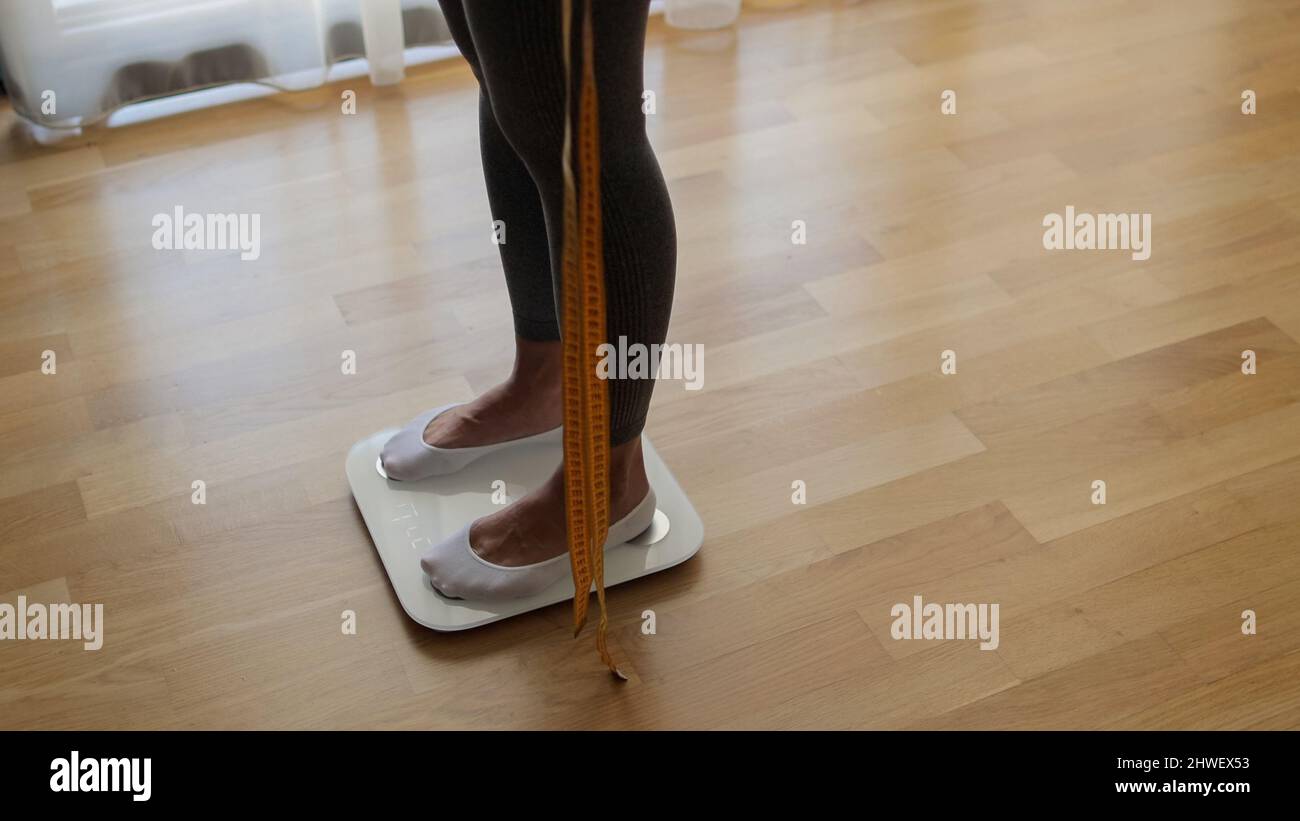 Woman Measuring Body Weight On Weighing Scale At Home Stock Photo - Alamy
