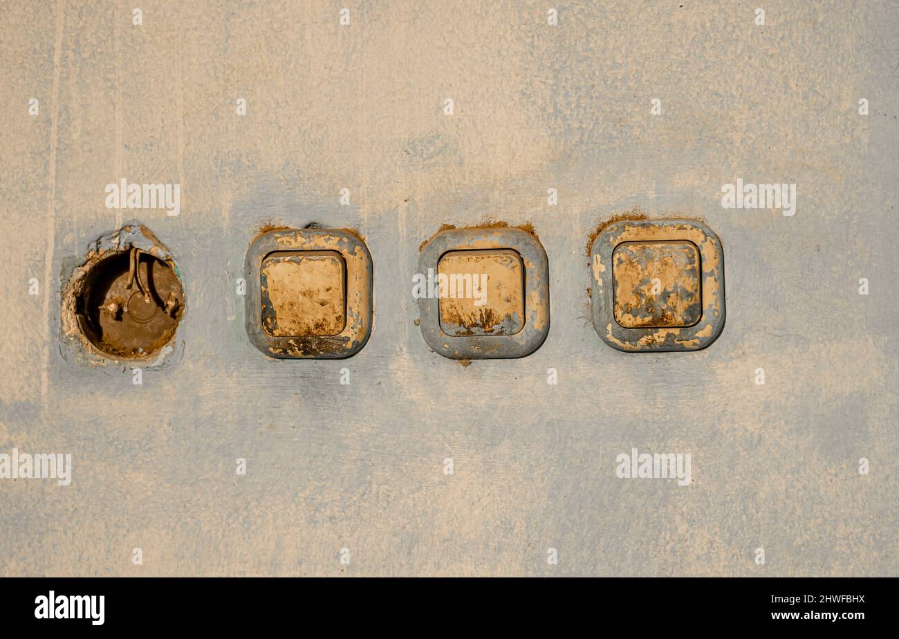 Row of dirty badly painted plastic light switches on a wall with hole ...