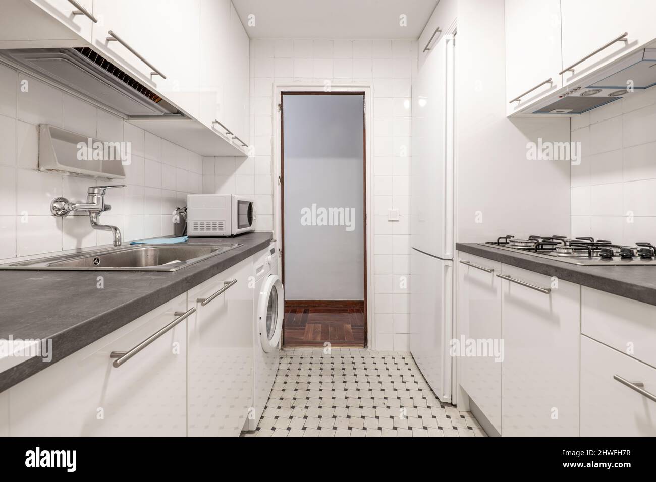 Kitchen with white furniture, gas stove, refrigerator and white washing ...