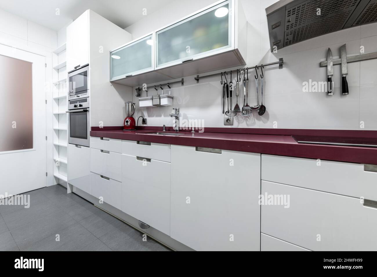 Elongated kitchen with white lacquered furniture with a long red ...