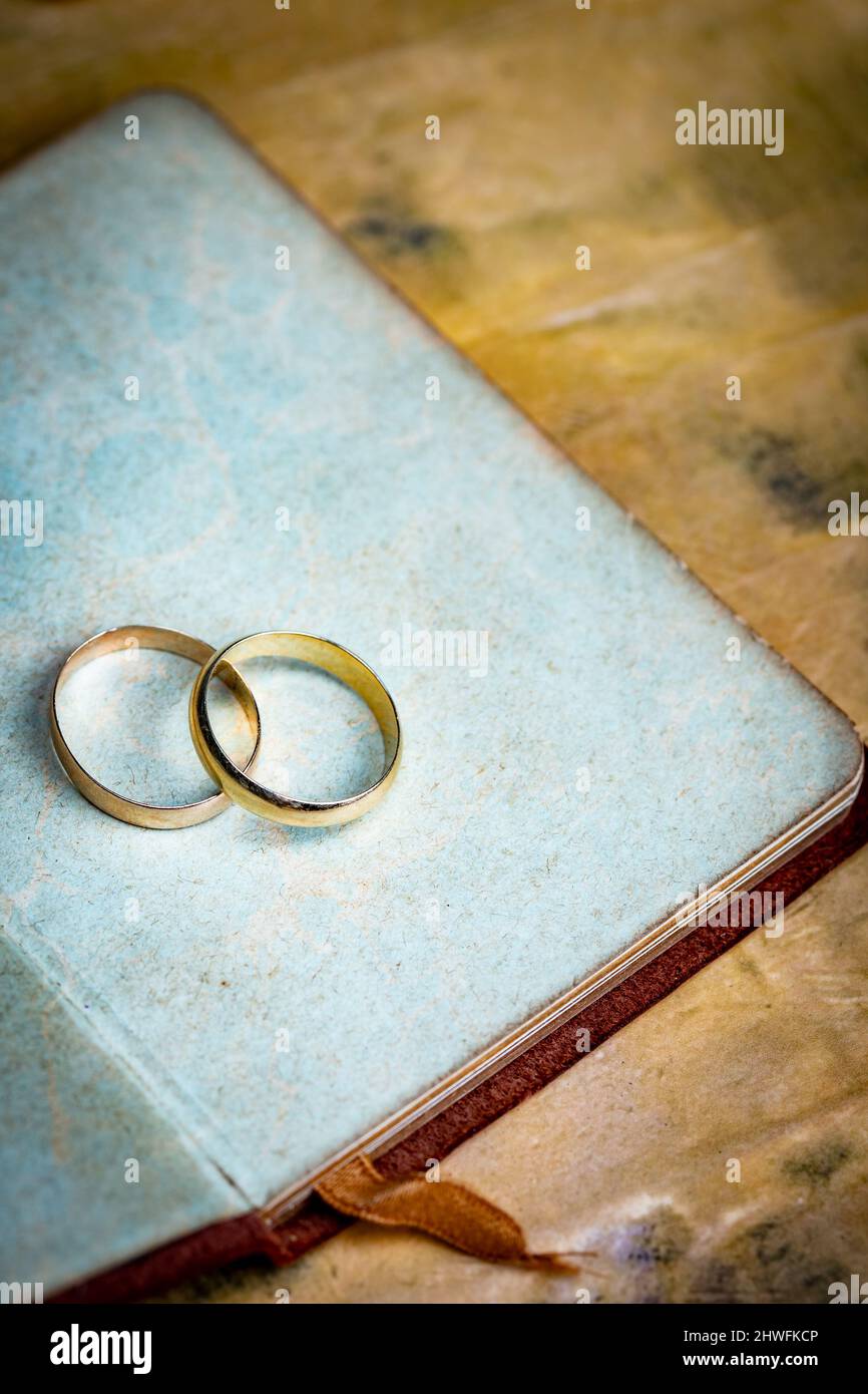 An pair of old, worn, gold wedding rings on the pages of a book Stock ...