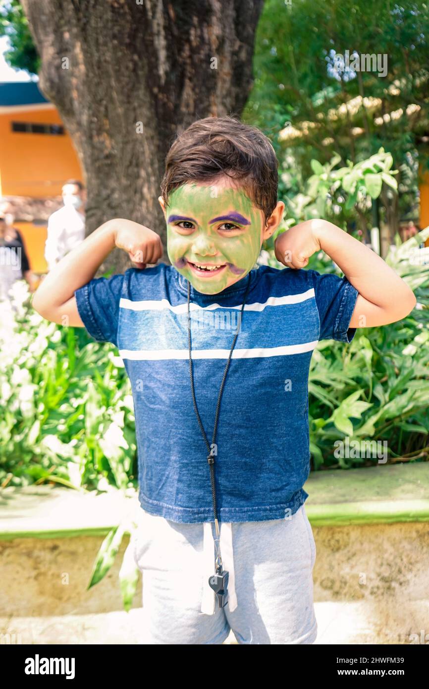 Vertical photo of a Latin boy with his face painted showin his muscles ...