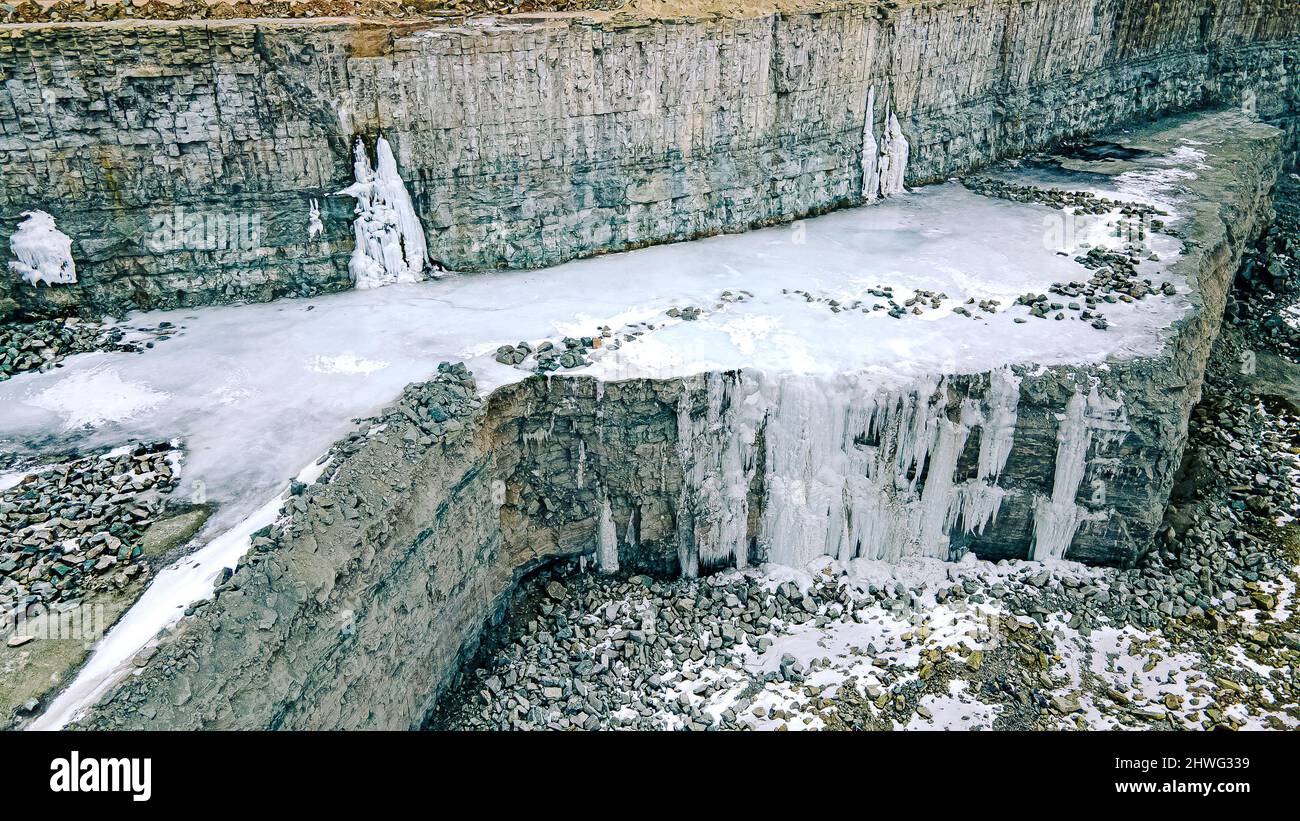 This rock quarry has a huge cut out in the ground with high cliffs ...