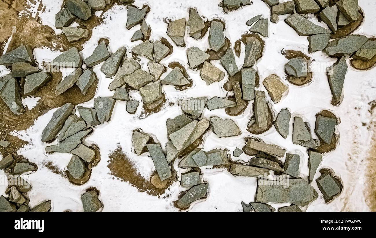Large rocks and stones collected at a rock quarry with snow melting on ...