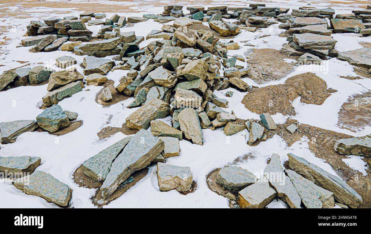 Large rocks and stones collected at a rock quarry with snow melting on ...