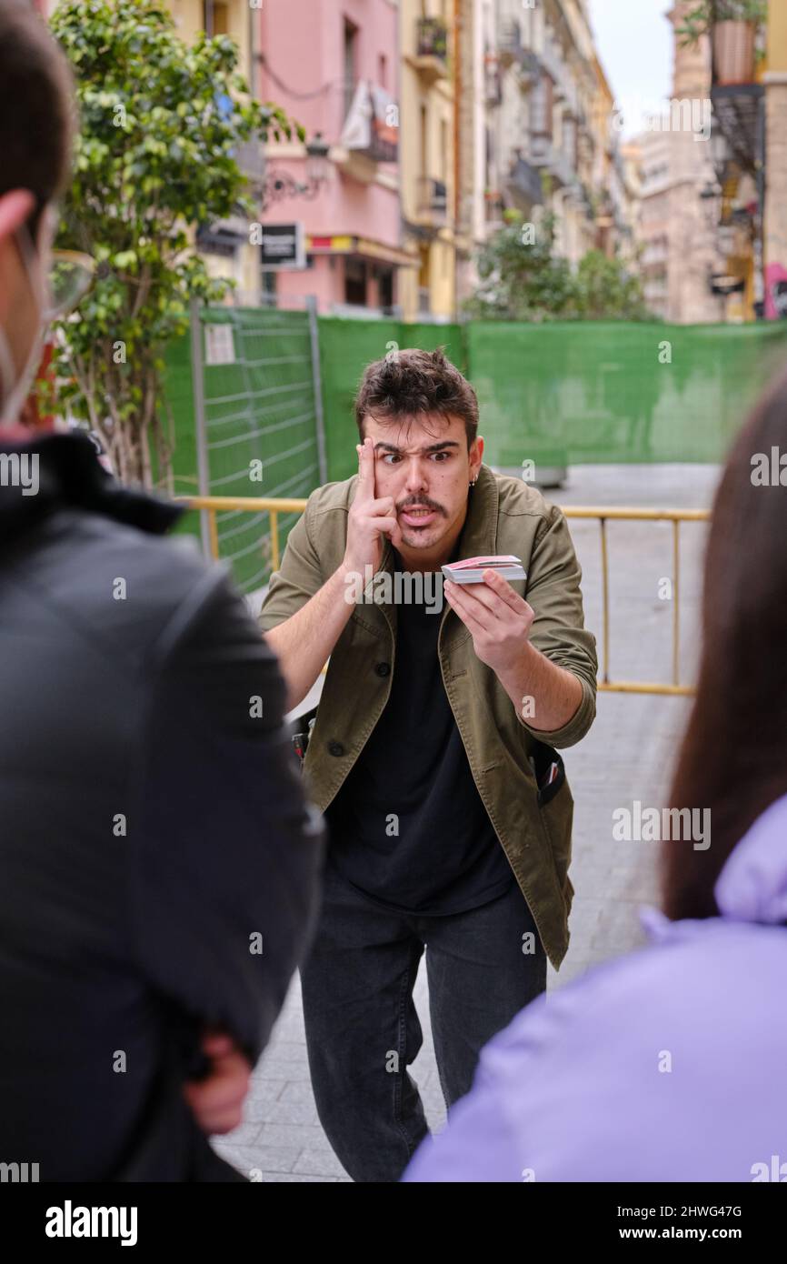 Concentrated street magician performing a card magic trick in front of ...
